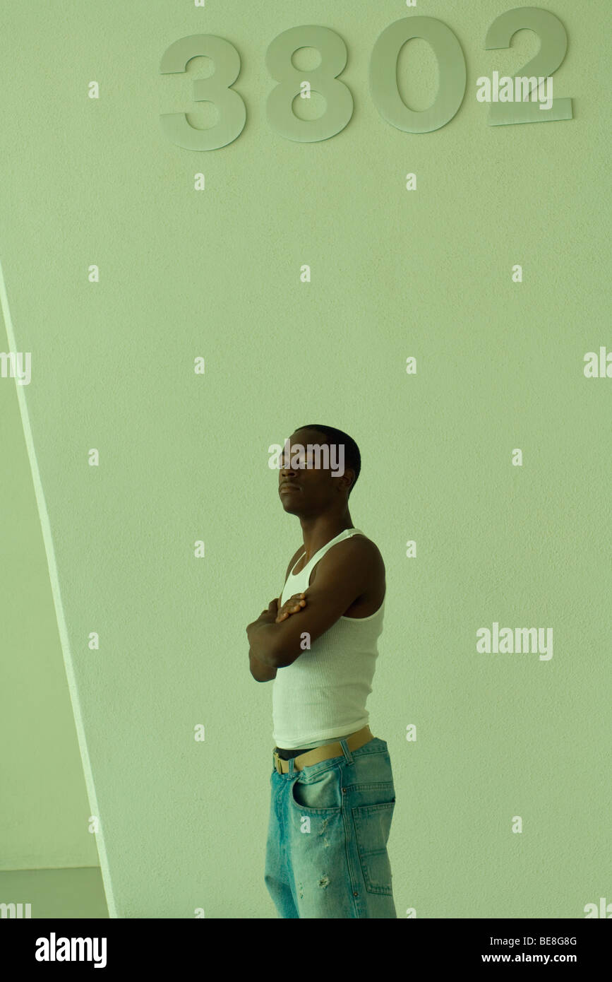 Young male standing with arms folded, looking defiantly at camera Stock ...
