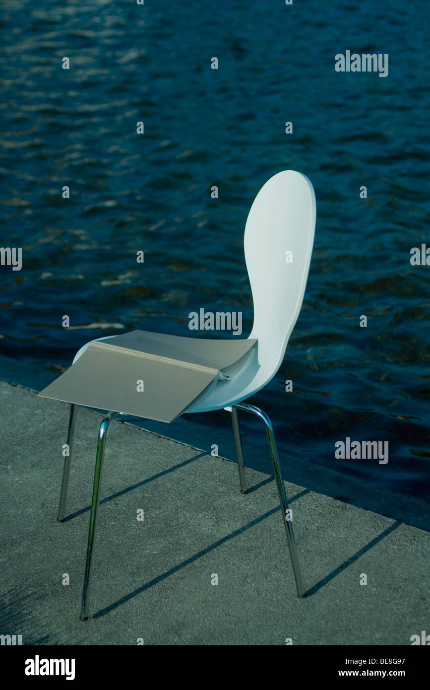 Open book placed face down on chair at end of lake pier Stock Photo - Alamy