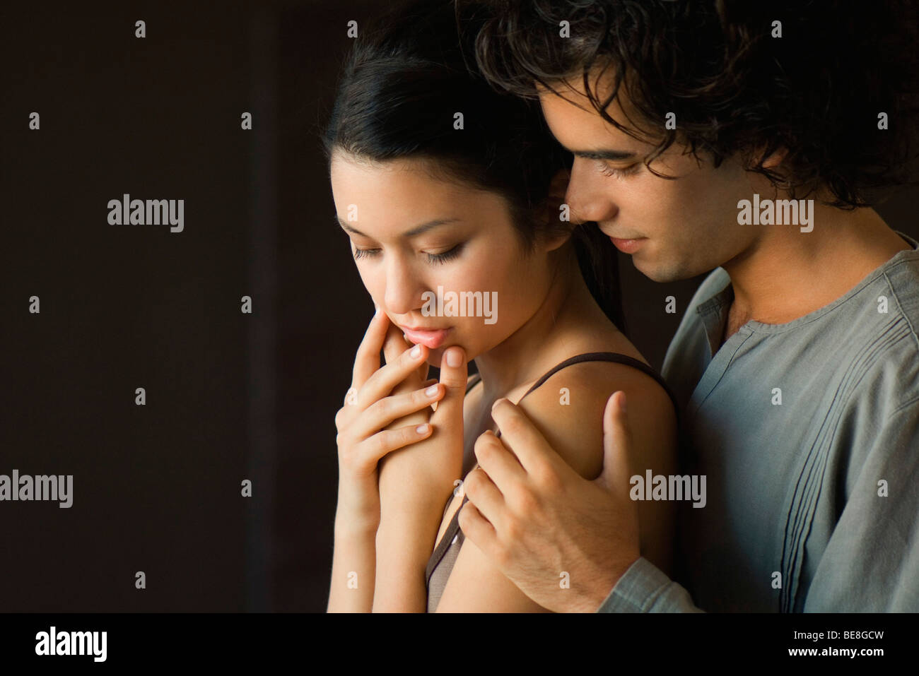 Couple together, man standing behind with hand on woman's shoulder ...