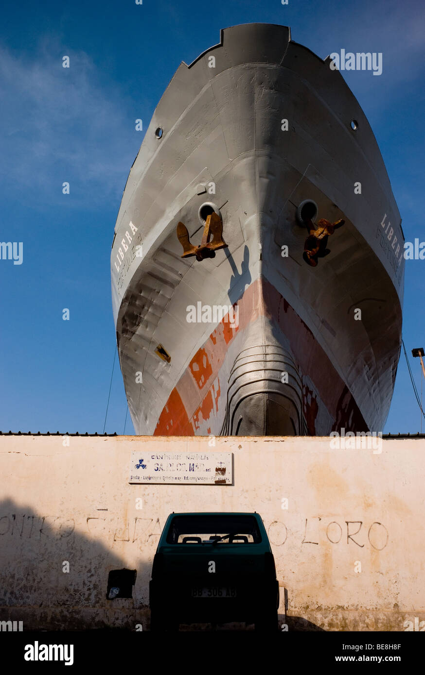 A ship in dry dock with it's bulbous bow sticking out into a car park ...