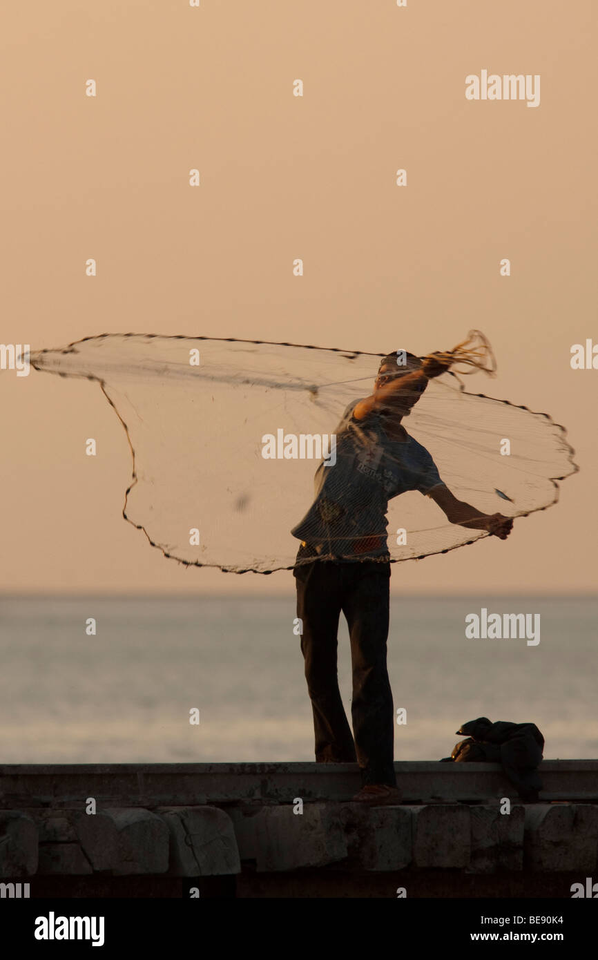 Boys trying to catch fish with a cast net as the sun goes down Stock ...