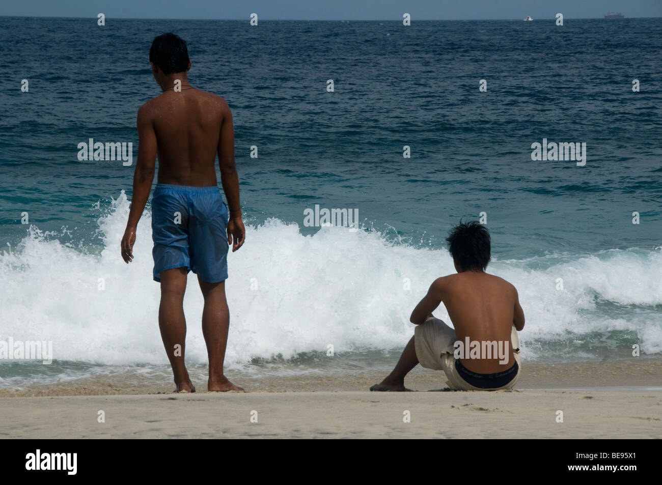 local boys watching the surf on the beach in Bali Indonesia Stock Photo ...