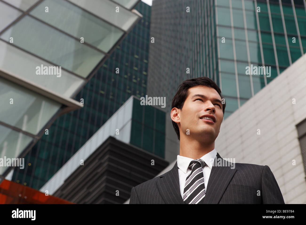 business man in suit standing among tall buildings Stock Photo - Alamy