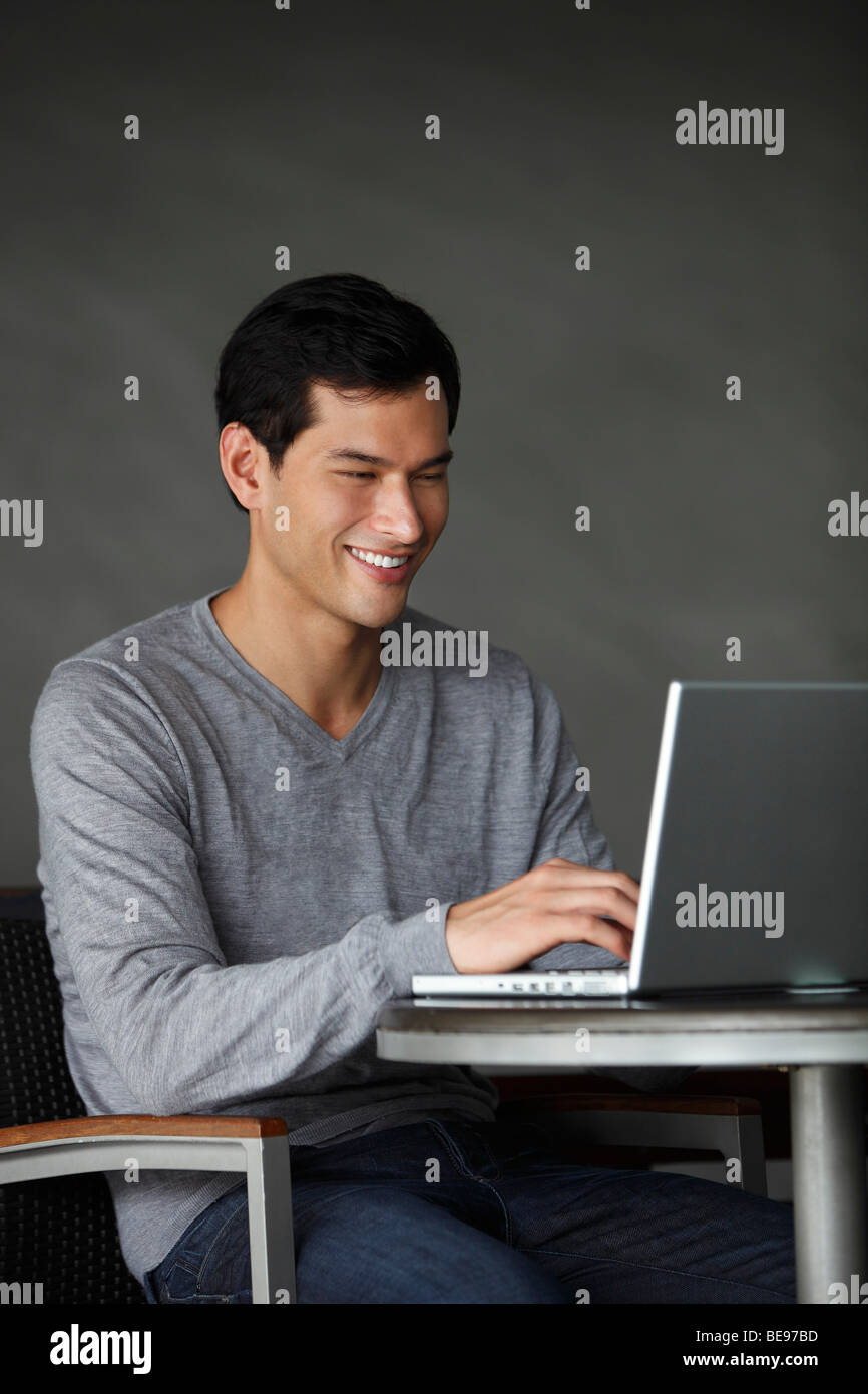 Asian man working on laptop, smiling Stock Photo - Alamy