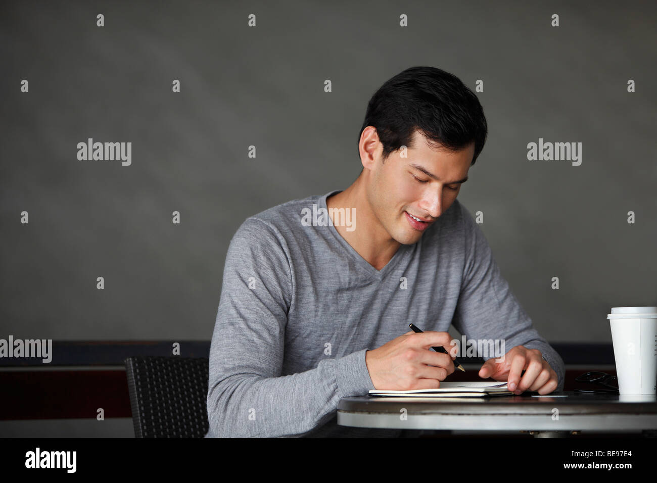 man writing in a book, smiling slightly Stock Photo - Alamy
