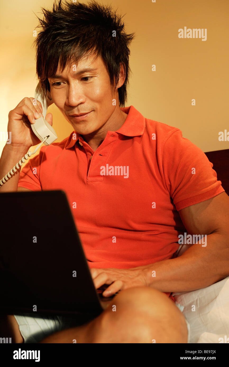 man talking on phone while on laptop Stock Photo - Alamy