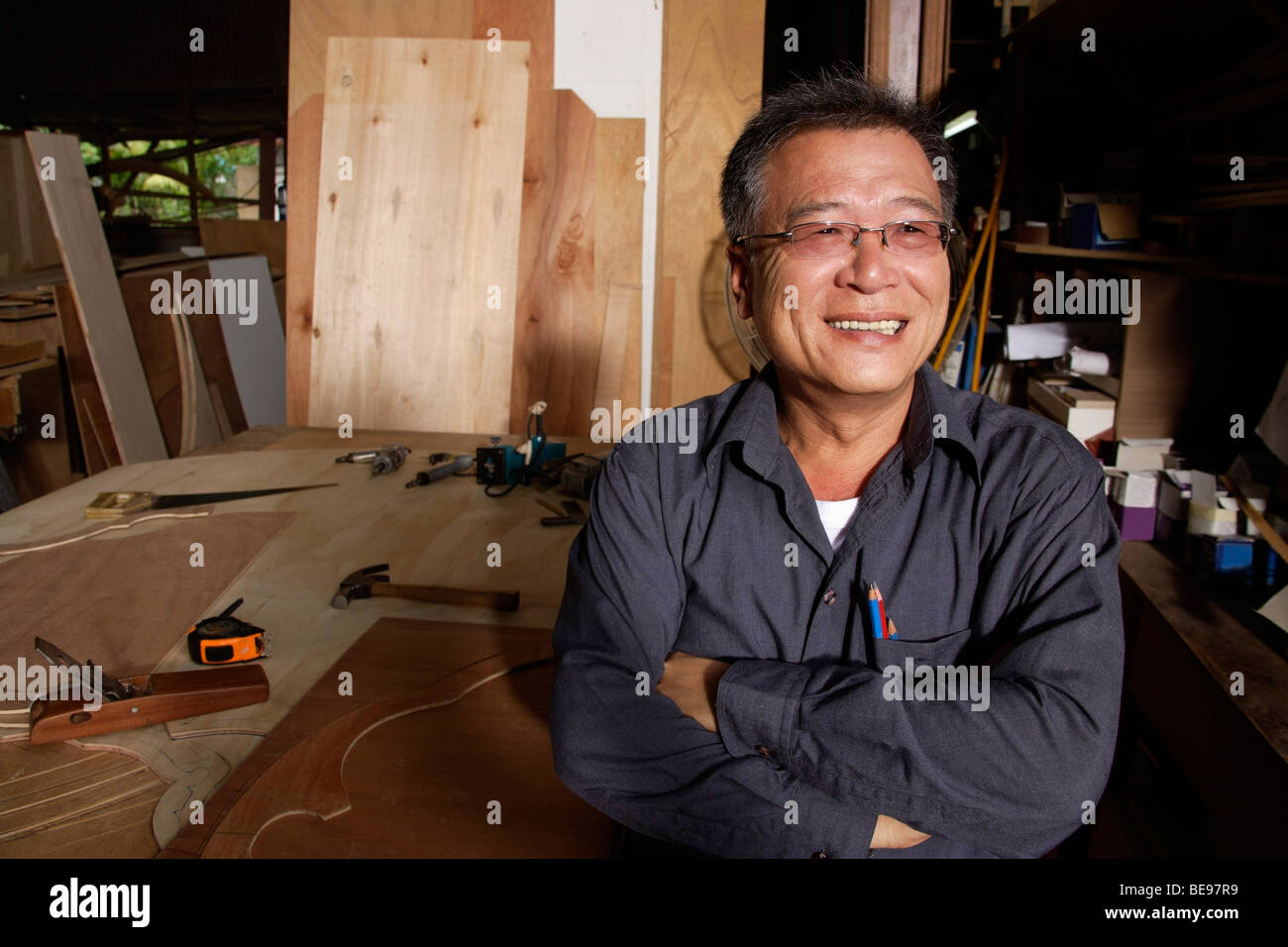 Smiling mature man in front of his work bench Stock Photo - Alamy