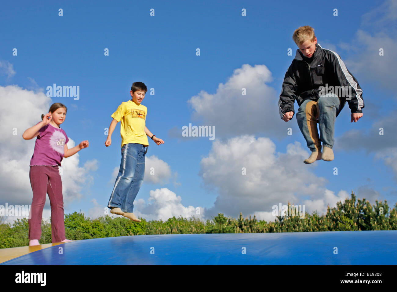 three kids jumping on a bouncy castle together, Denmark Stock Photo - Alamy