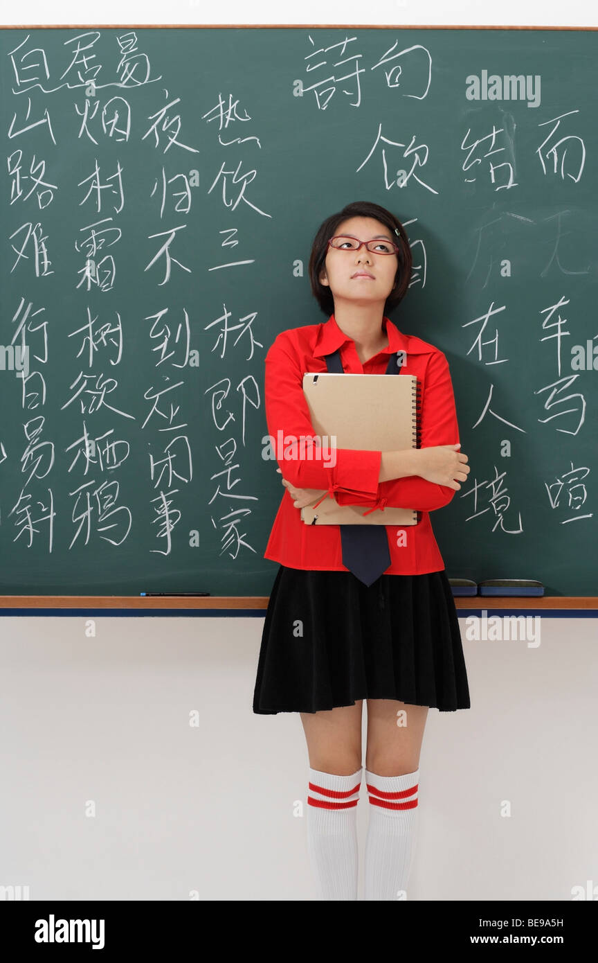 student standing in front of chinese characters written on chalk board ...