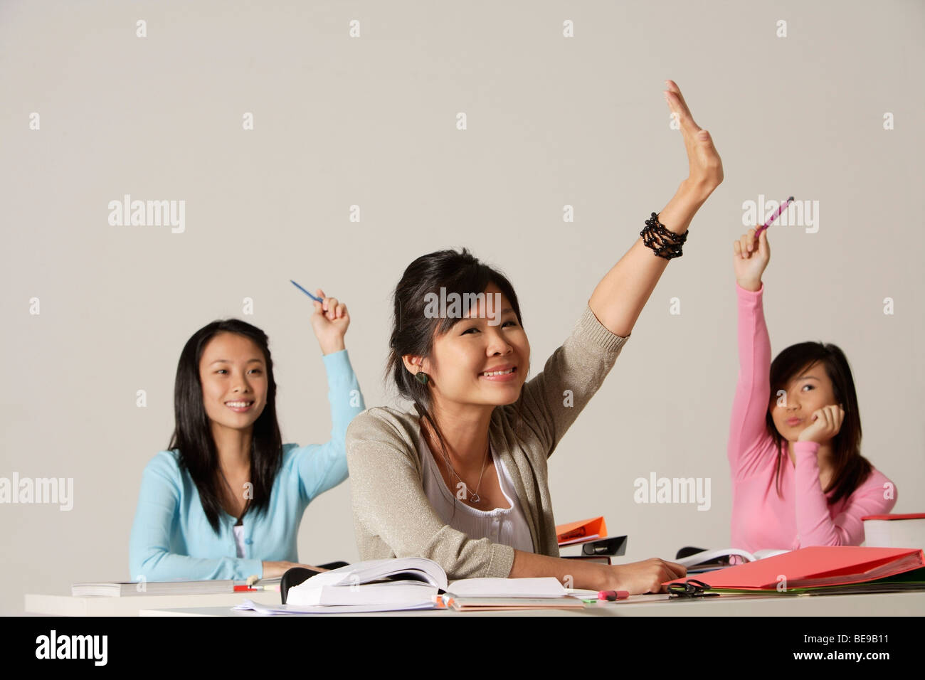 Three women raising their hands in class Stock Photo - Alamy