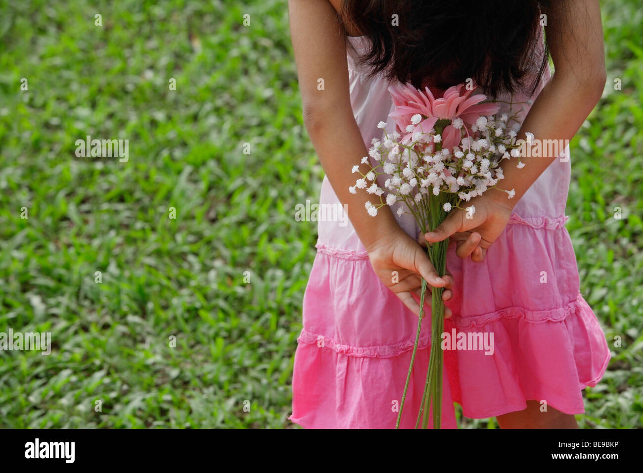 A small girl holds flowers behind her back Stock Photo - Alamy