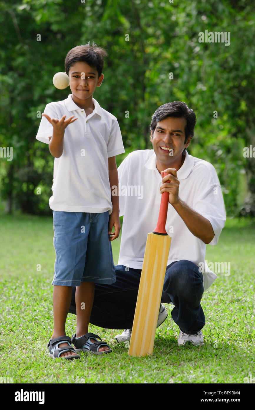 A father and son look at the camera as they play cricket together Stock ...