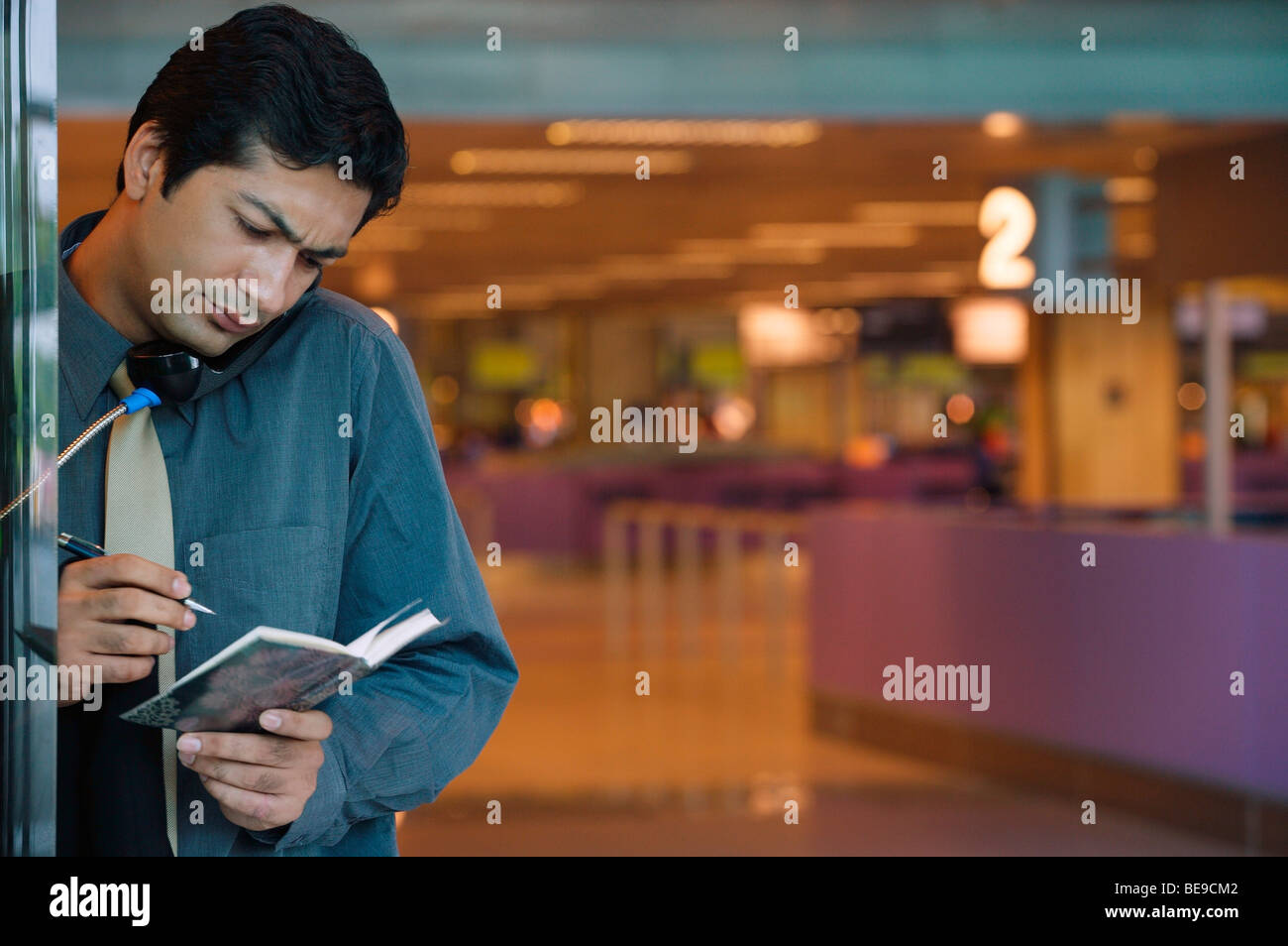 Man making notes while on the phone Stock Photo - Alamy