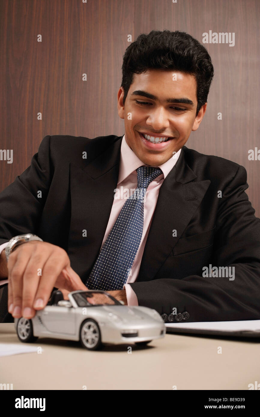 Businessman playing with toy car Stock Photo - Alamy