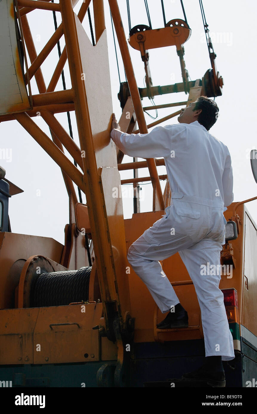 Man in work uniform getting onto crane Stock Photo - Alamy