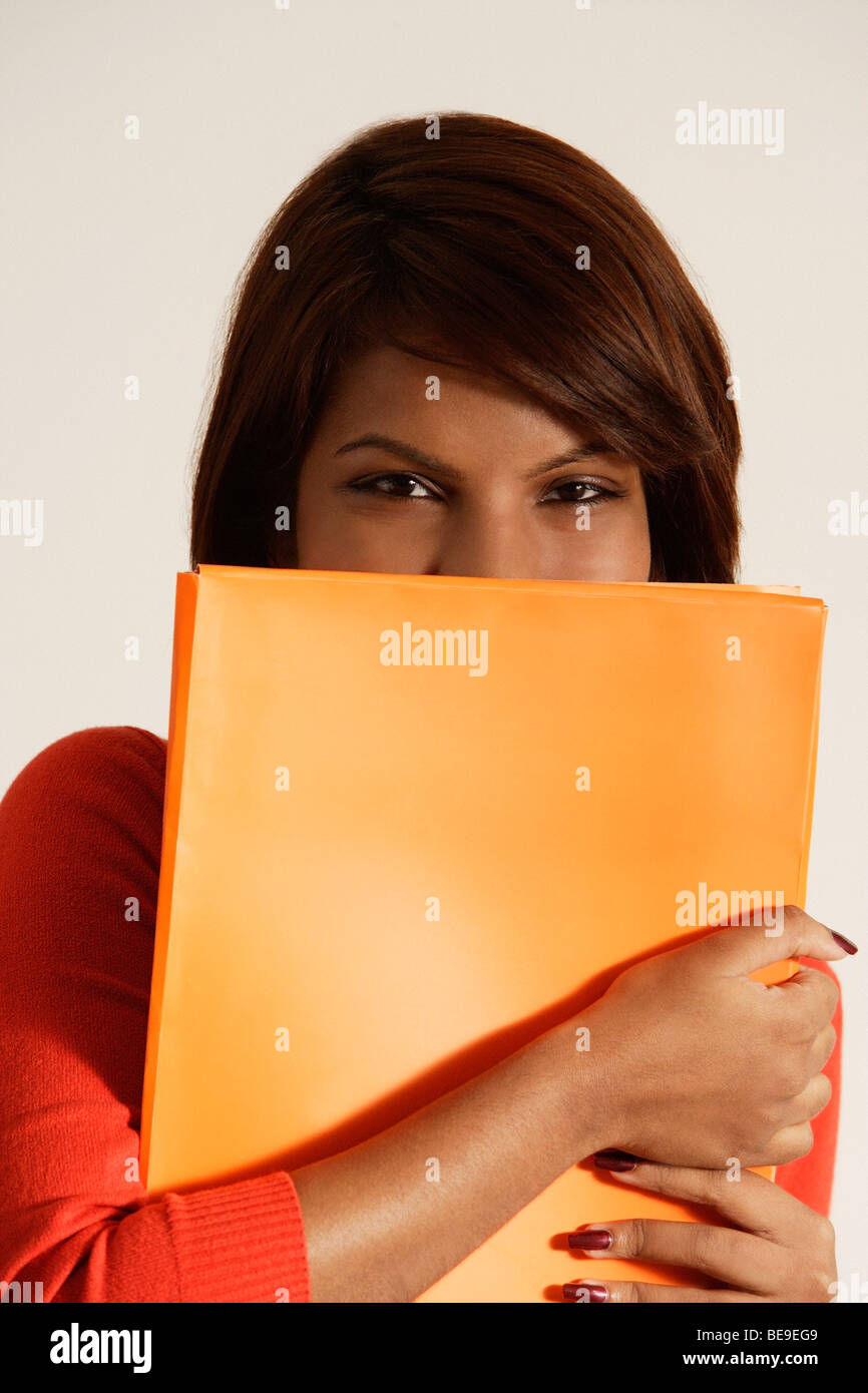 Business woman holding a orange work file in front of her face Stock ...