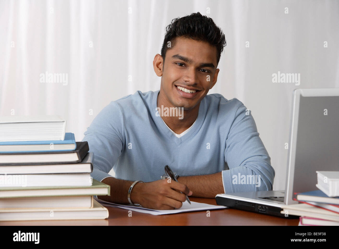 young man sitting at his desk, writing Stock Photo - Alamy