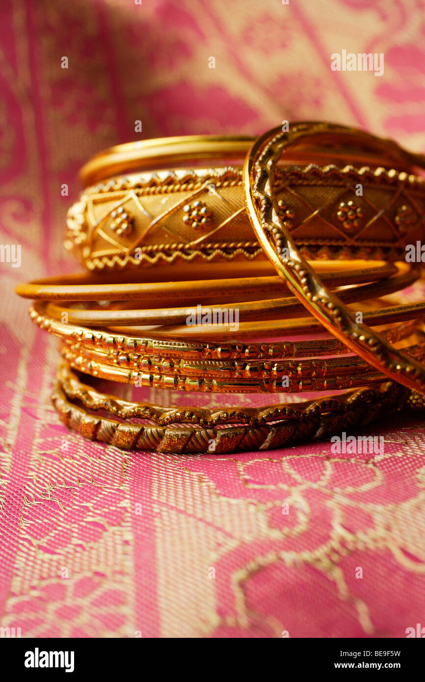 gold Indian bangles on pink sari cloth Stock Photo - Alamy