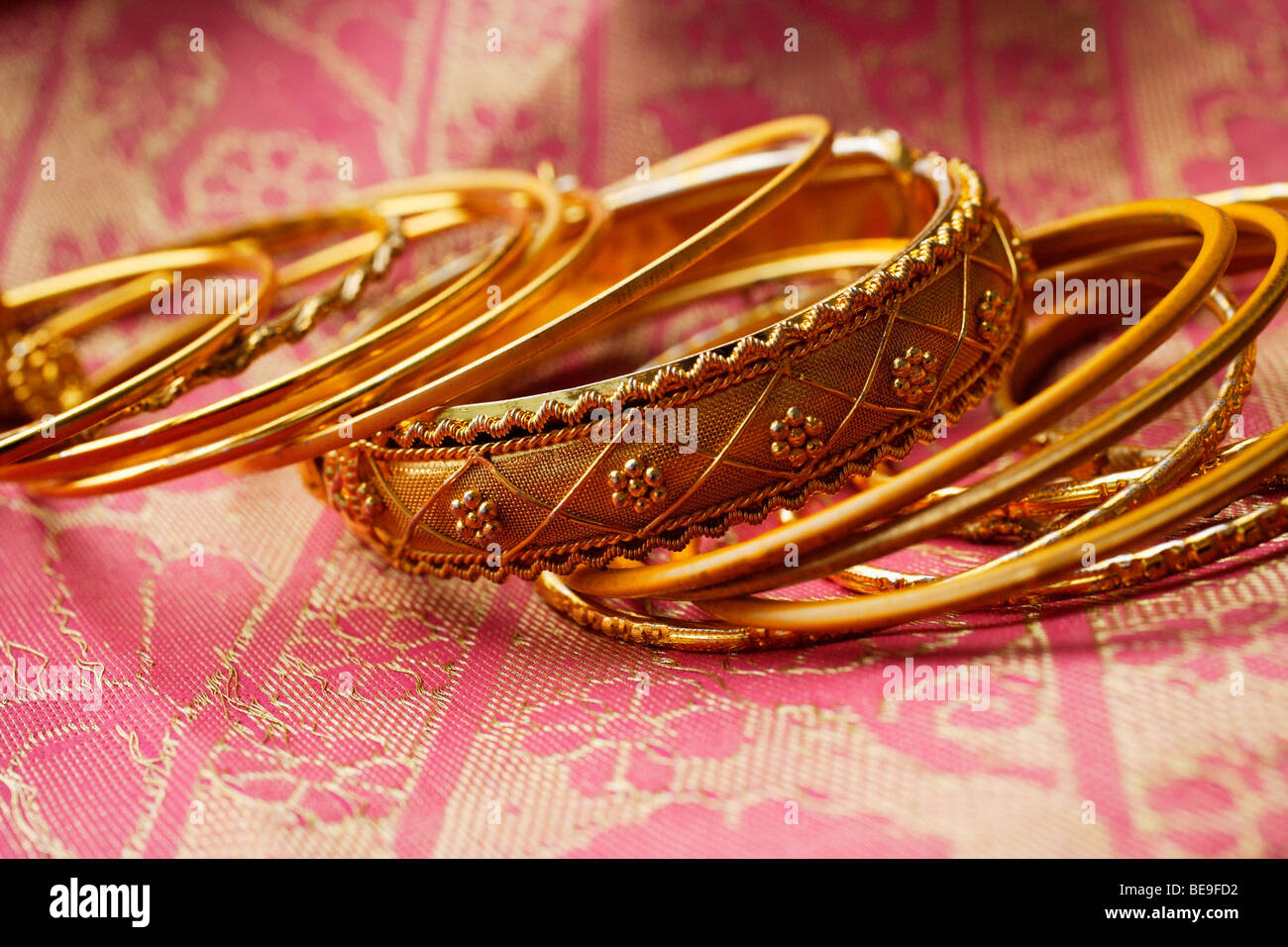 gold Indian bangles on pink sari cloth Stock Photo - Alamy