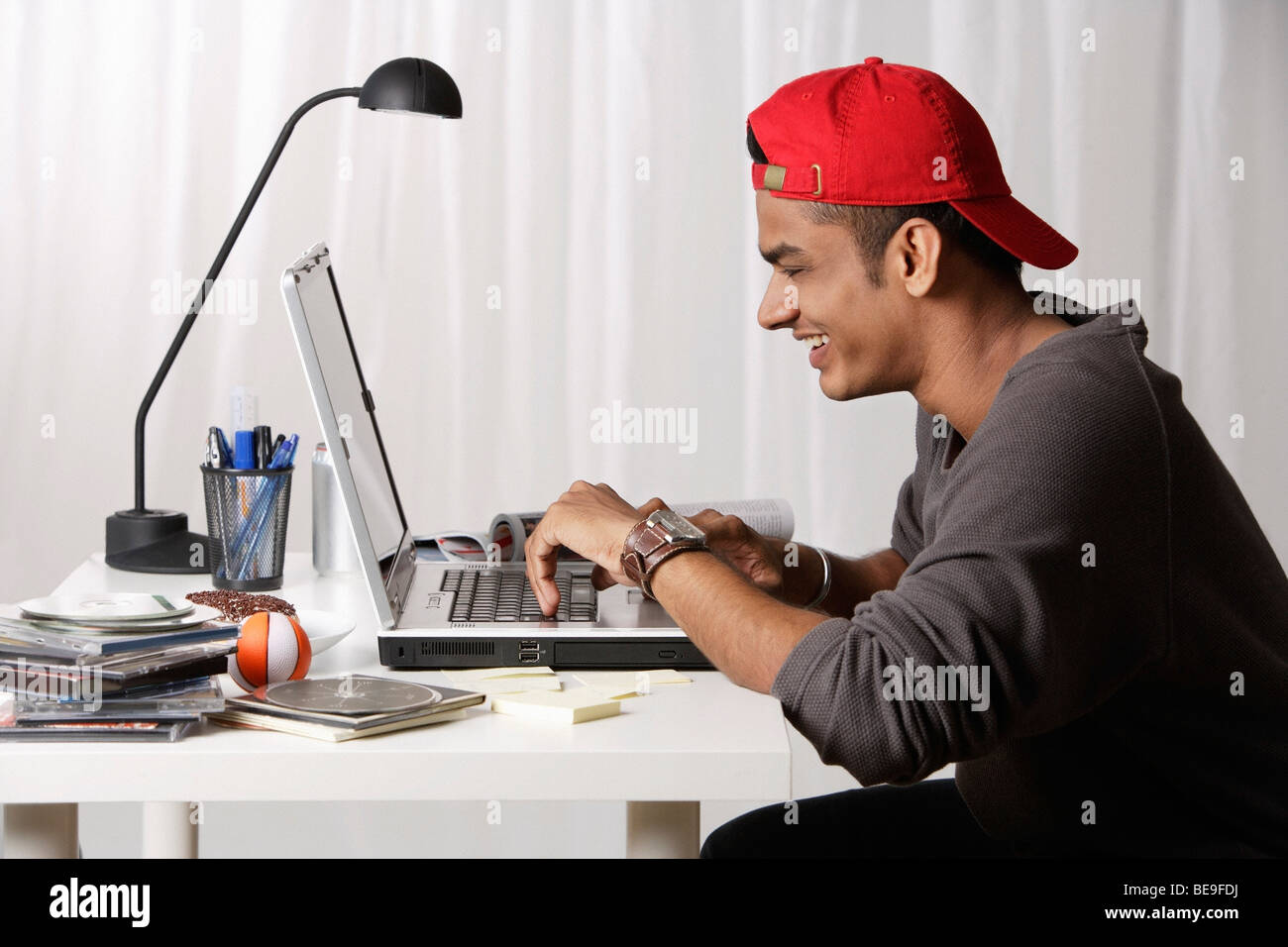 young man with red cap working on laptop Stock Photo - Alamy