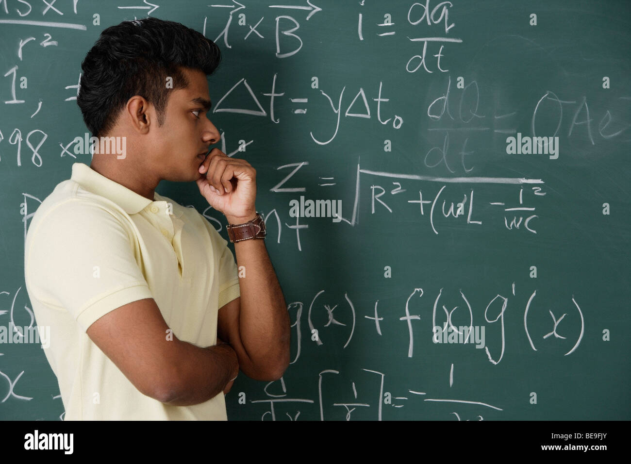 young man standing in front of chalkboard, thinking Stock Photo - Alamy