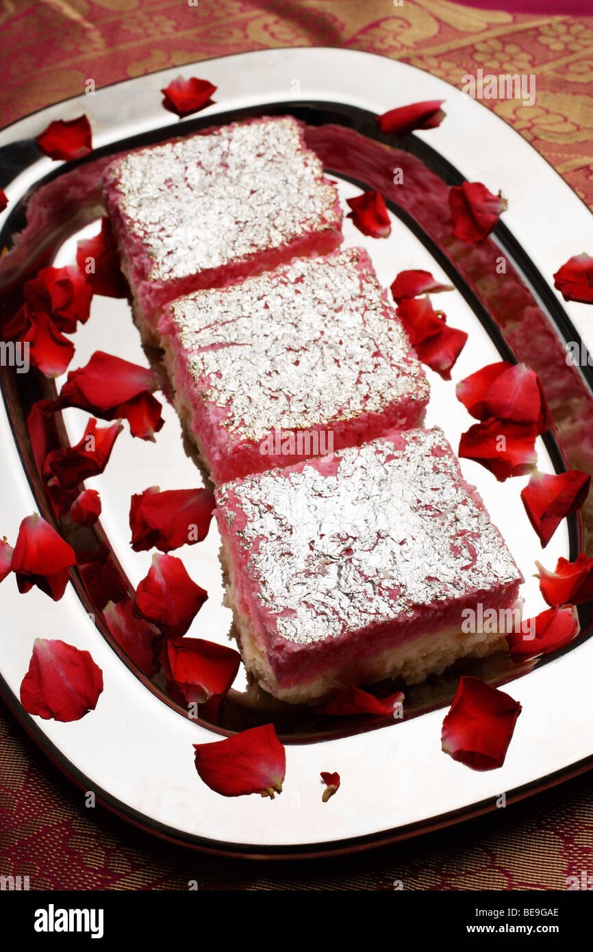 Indian pink sweets on silver tray with rose petals Stock Photo - Alamy