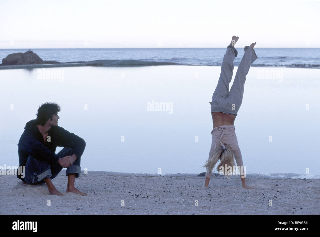 Young couple relaxing on beach at dusk Stock Photo - Alamy