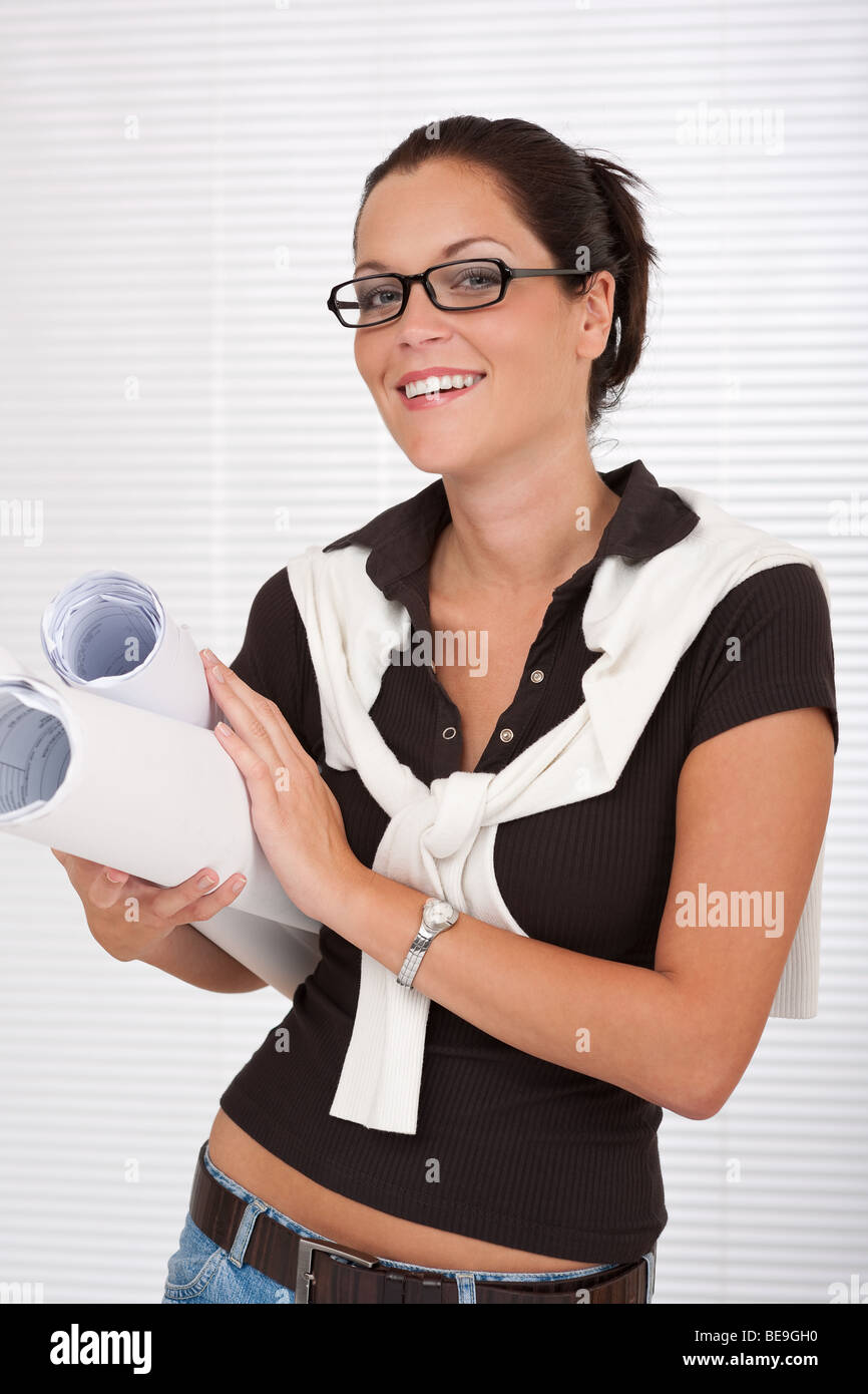 Smiling successful architect woman holding plans at the office Stock ...