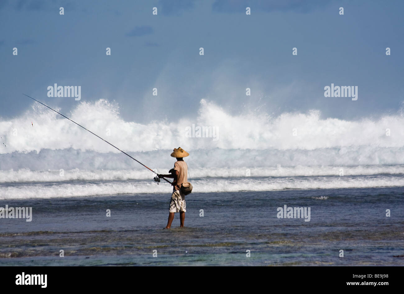 One fisherman with conical hat fishing sheltered by the coral reef with ...