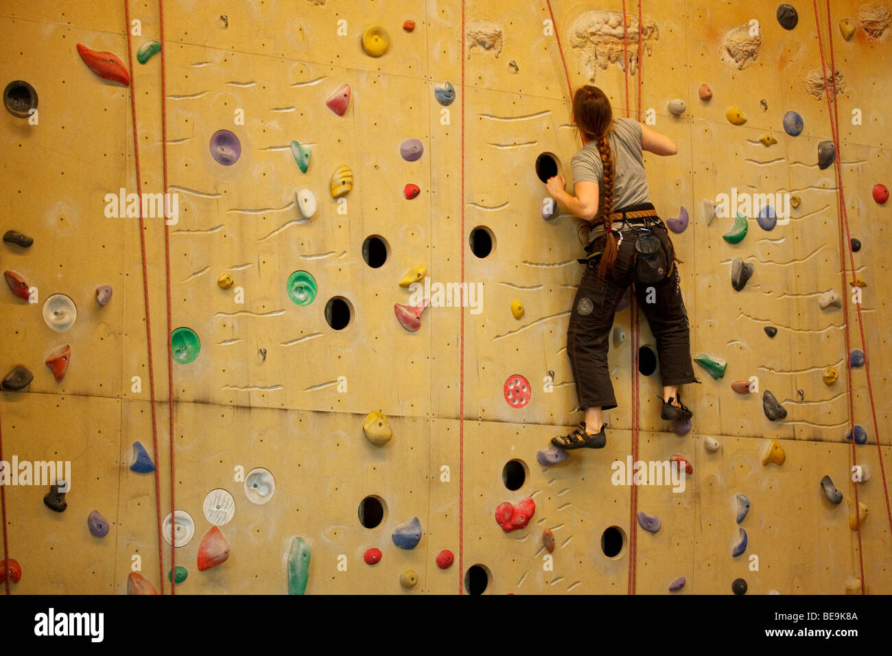 Mesije klimt met behulp van touw tegen een klimwand. Girl climbing ...