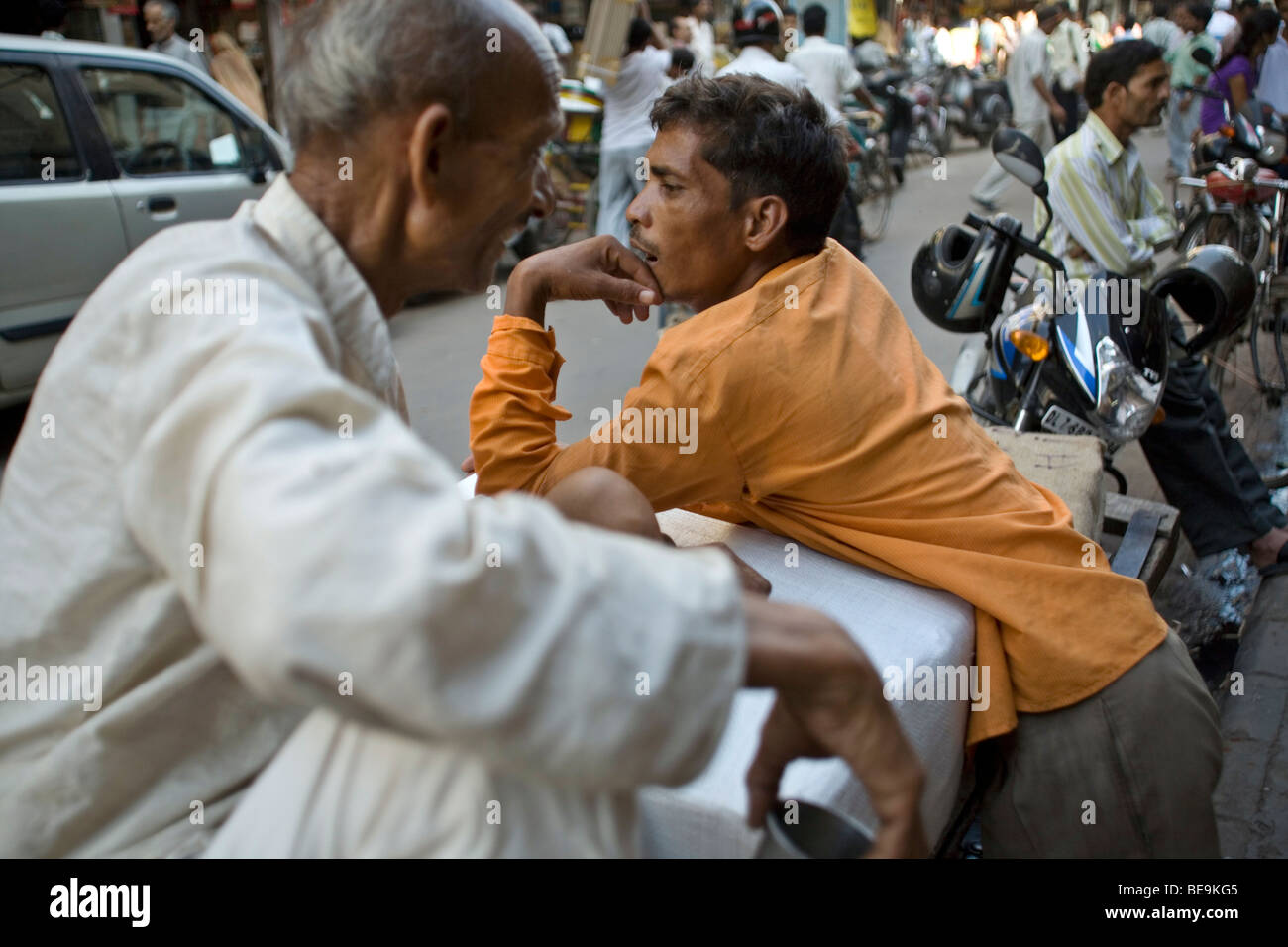 Two men talk whilst one leans on a motorbike in Old Delhi, India Stock ...