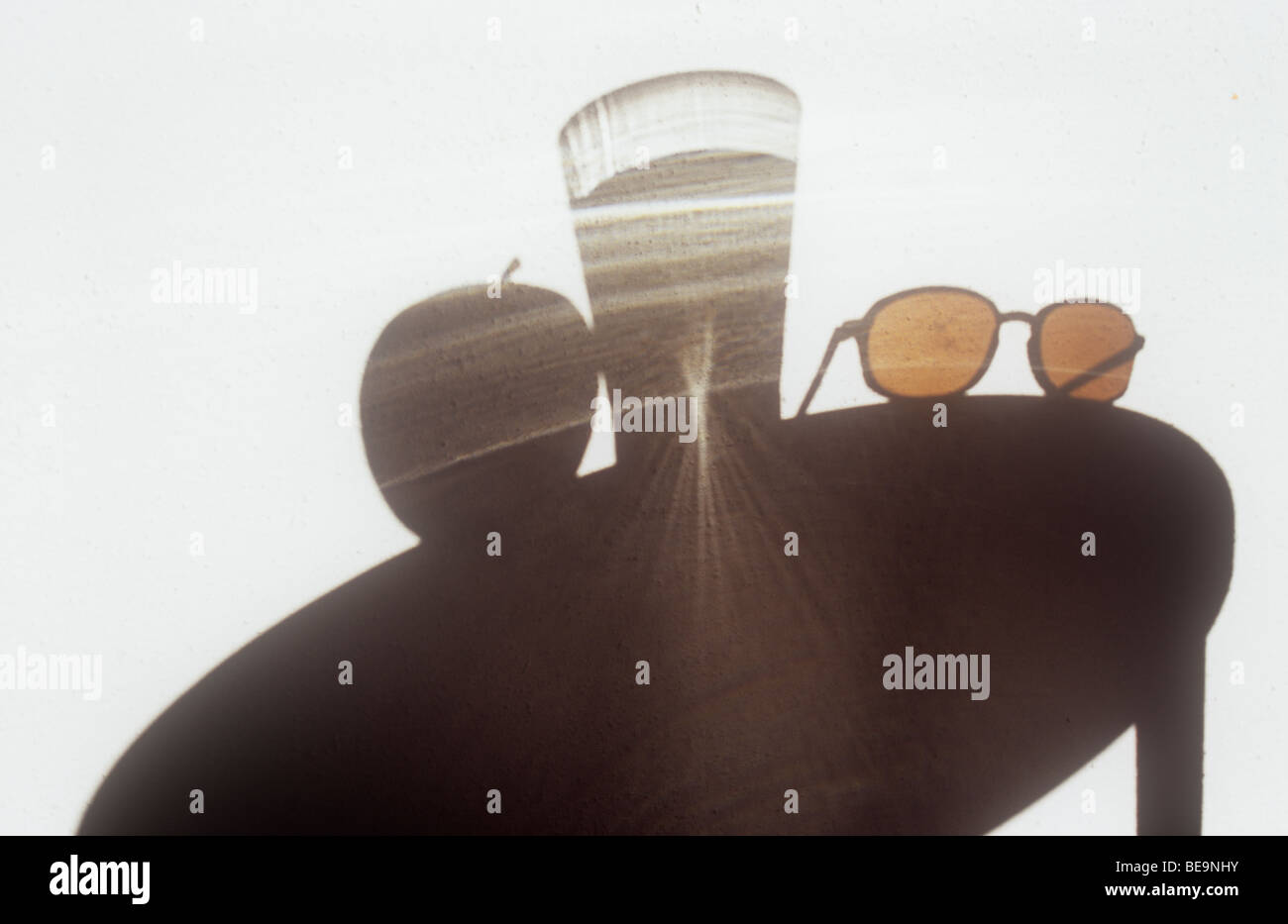 Shadow on white textured wall of circular table with apple and ...