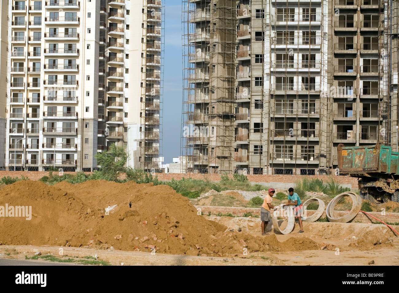 Labourers moving drain pipes in front of a construction site in Gurgaon ...