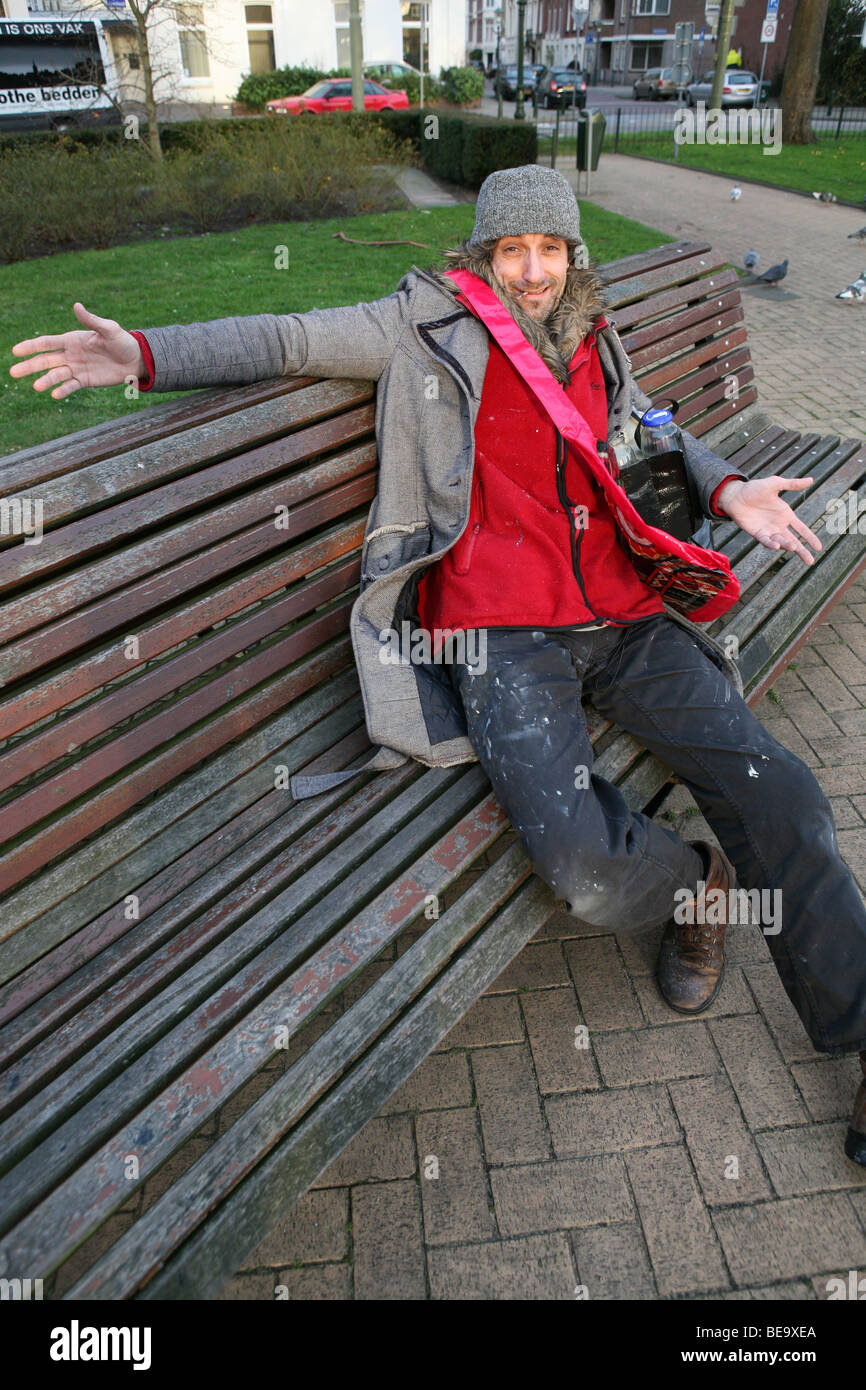 Crazy and happy homeless wanderer sitting on bench outside Stock Photo ...
