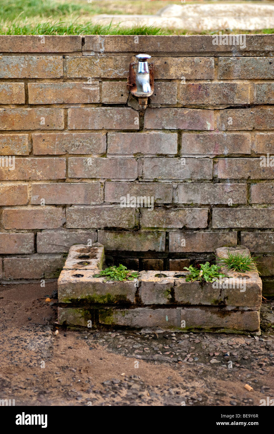 Water tap set in a brick wall with drain Stock Photo - Alamy