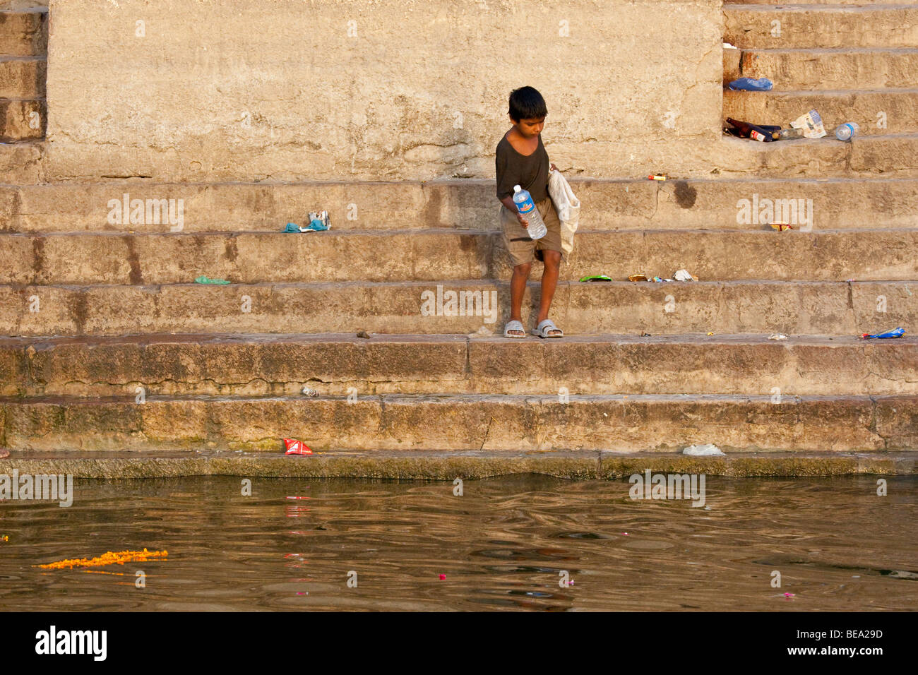 Boy collecting plastic bottles at the Ganges River in Varanasi India ...