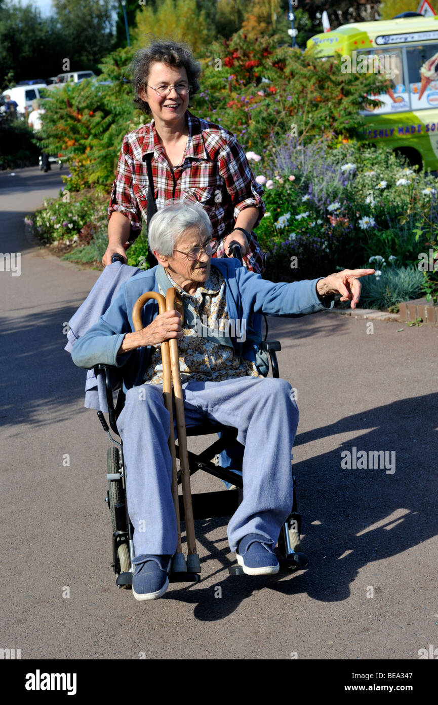 Middle aged daughter taking elderly mother in wheelchair for outing ...