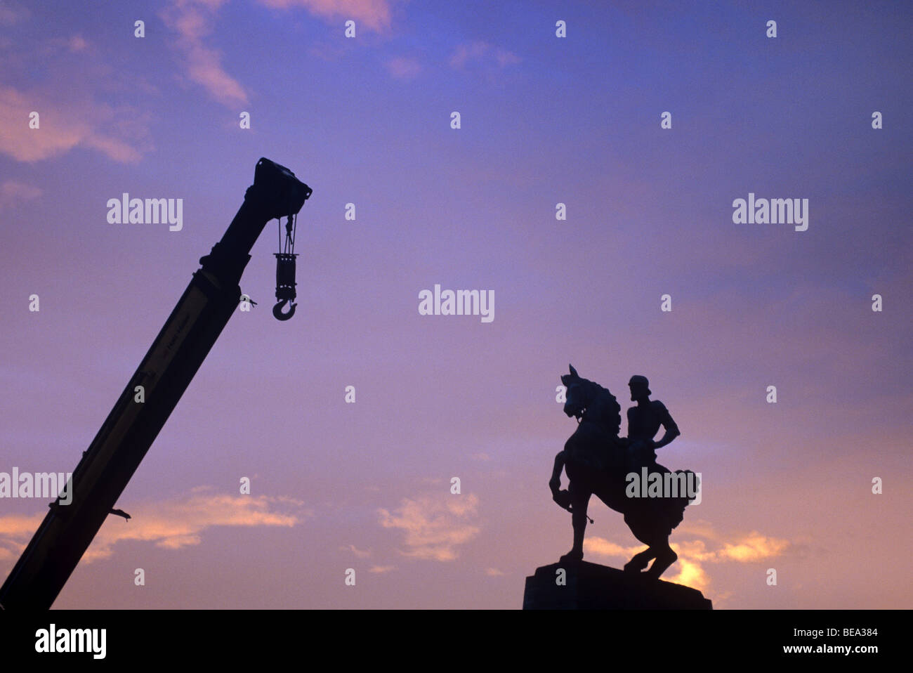 Building crane and statue against sunset sky Stock Photo - Alamy