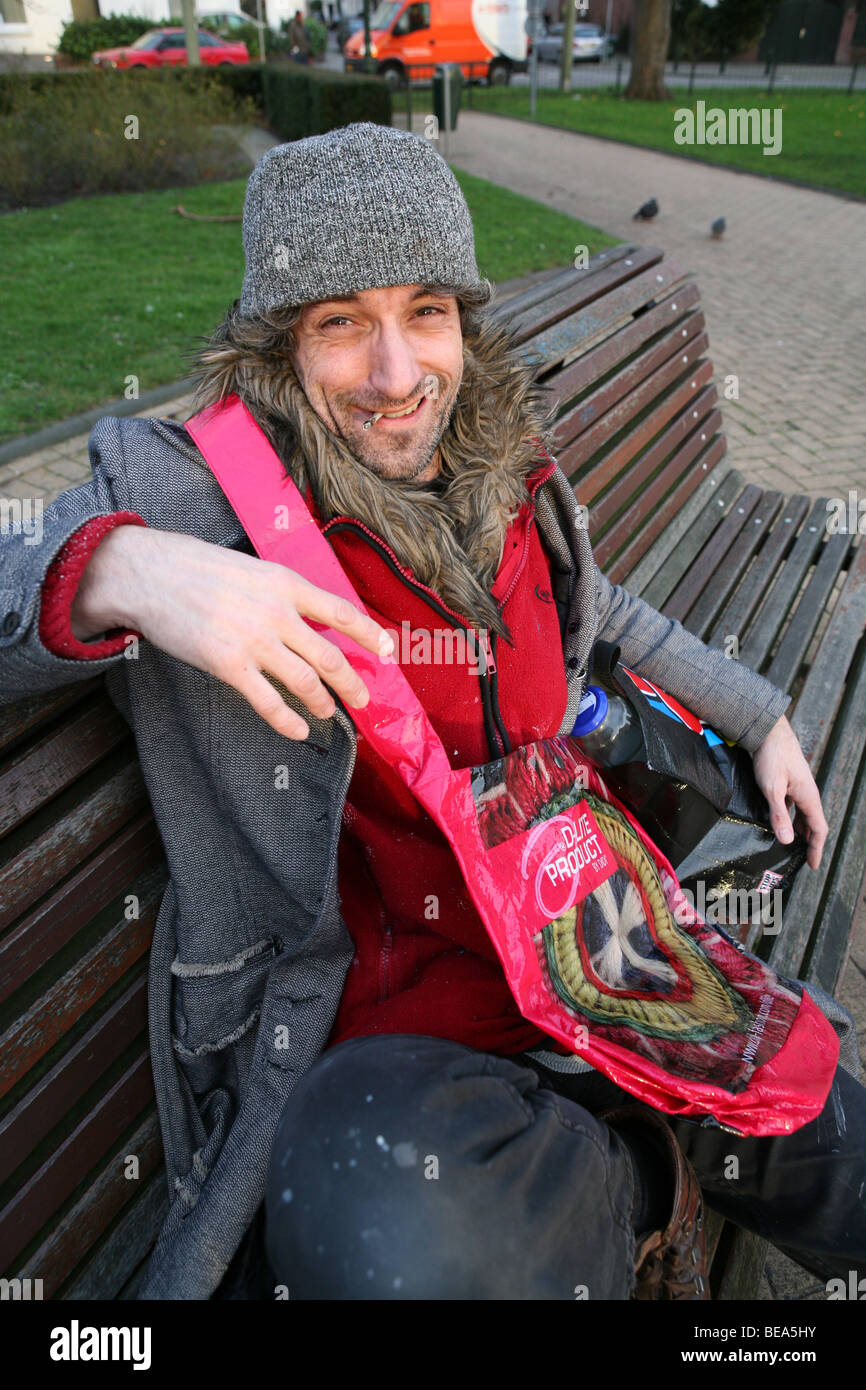 Crazy and happy homeless wanderer sitting on bench outside Stock Photo ...