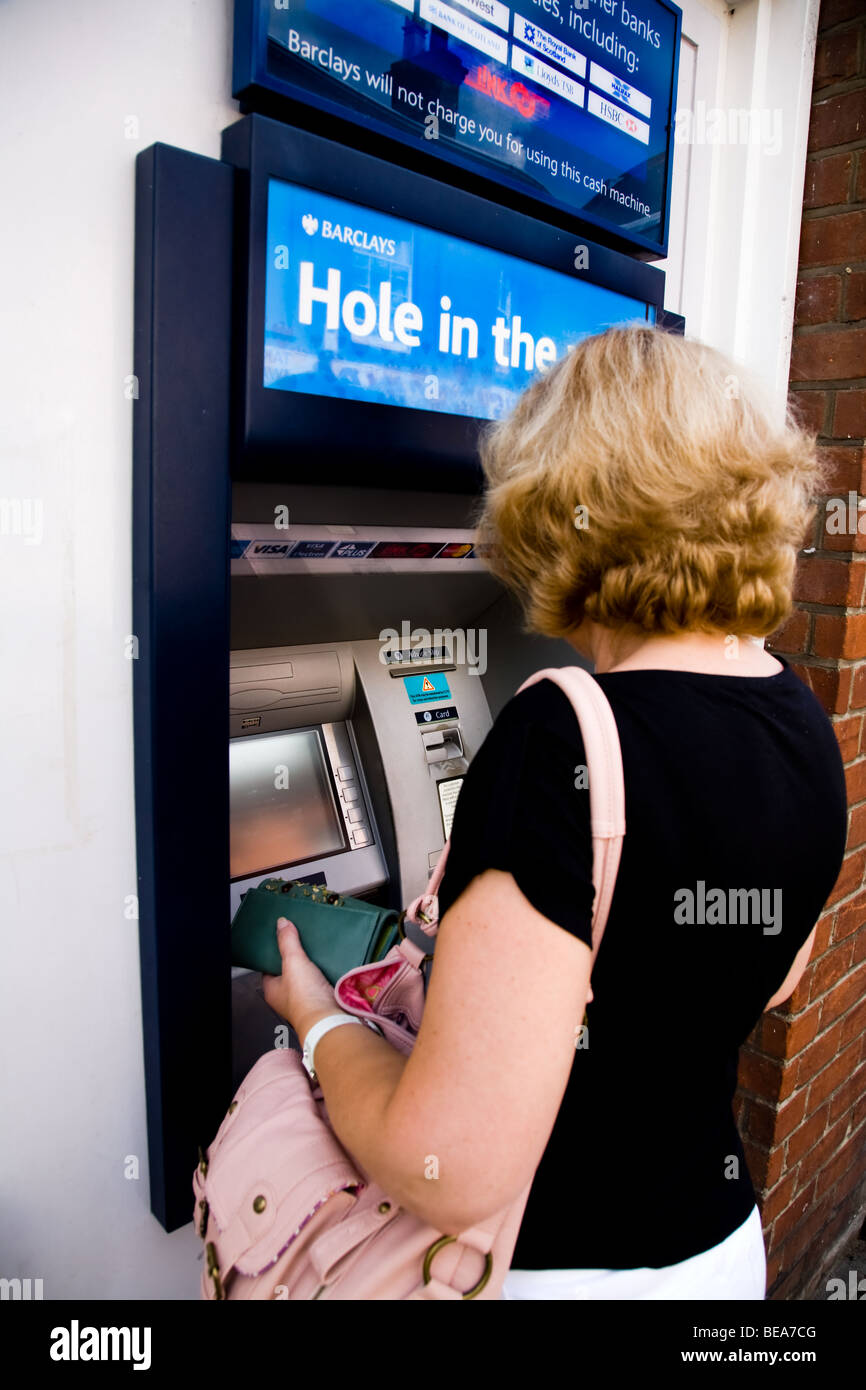 A BARCLAYS BANK HOLE IN THE WALL MACHINE SET IN A MAIN STREET . A WOMAN ...