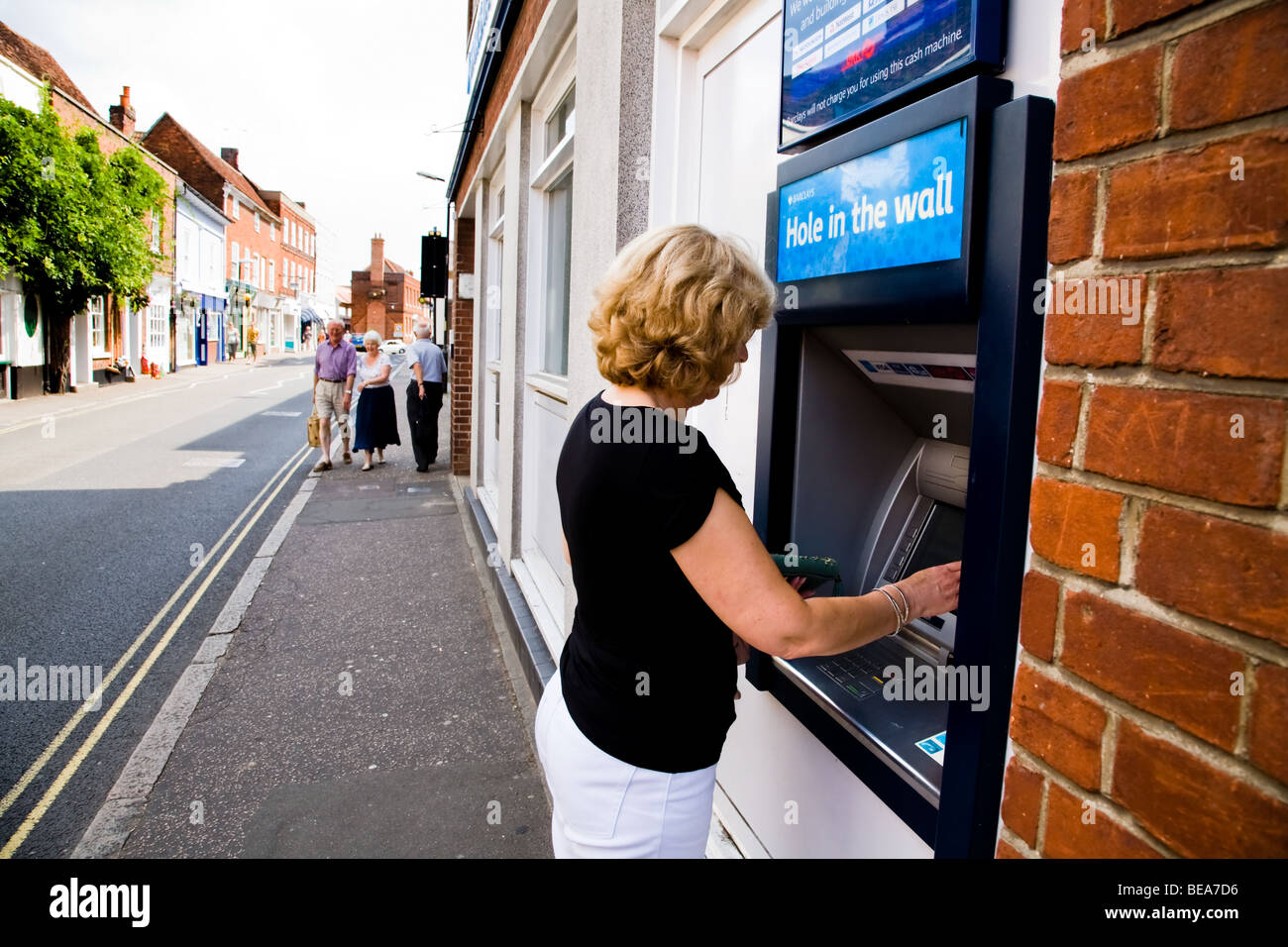 A BARCLAYS BANK HOLE IN THE WALL MACHINE SET IN A MAIN STREET . A WOMAN ...