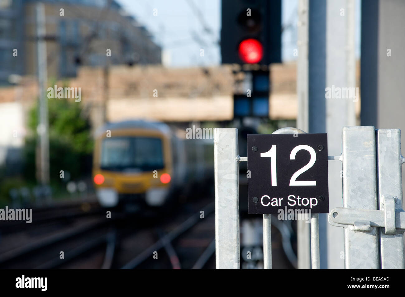 Platform sign at a railway station with red signal and train pulling in ...
