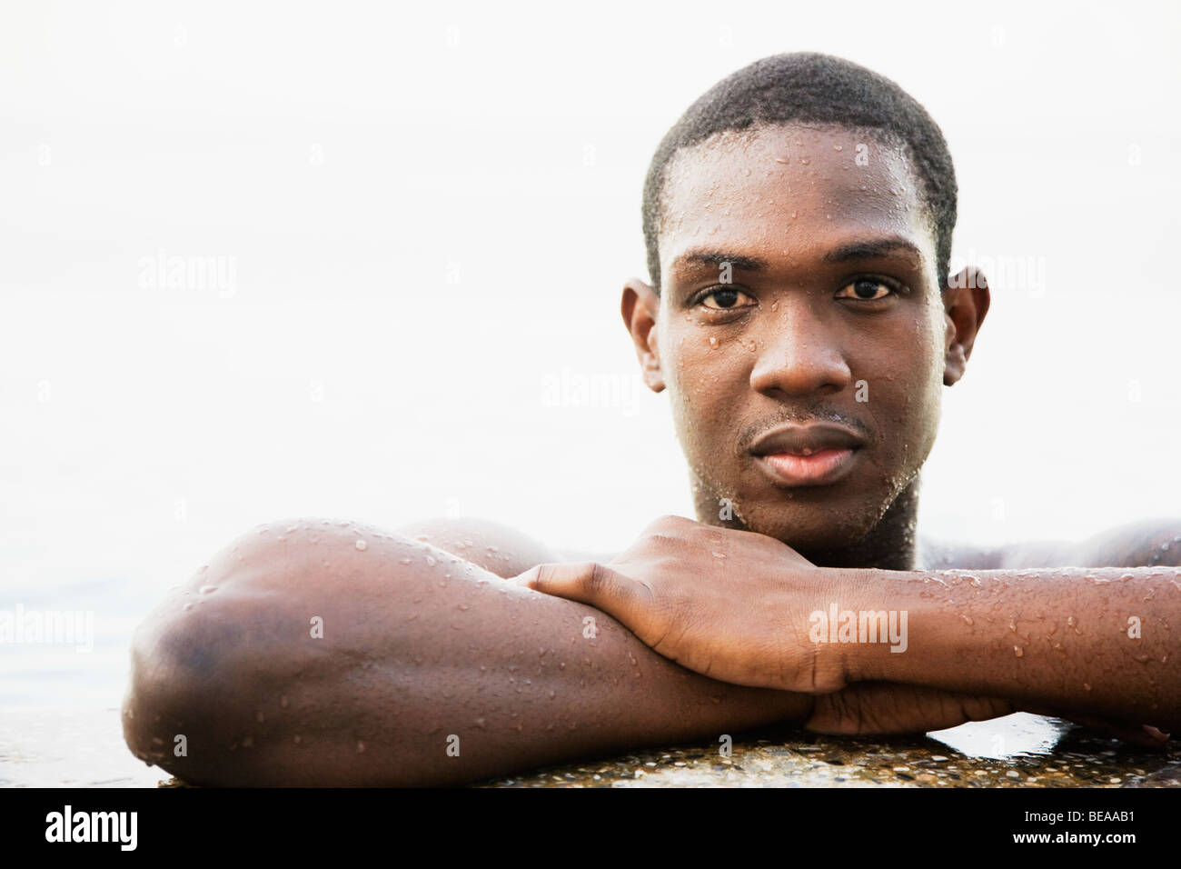 African man leaning on edge of swimming pool Stock Photo - Alamy