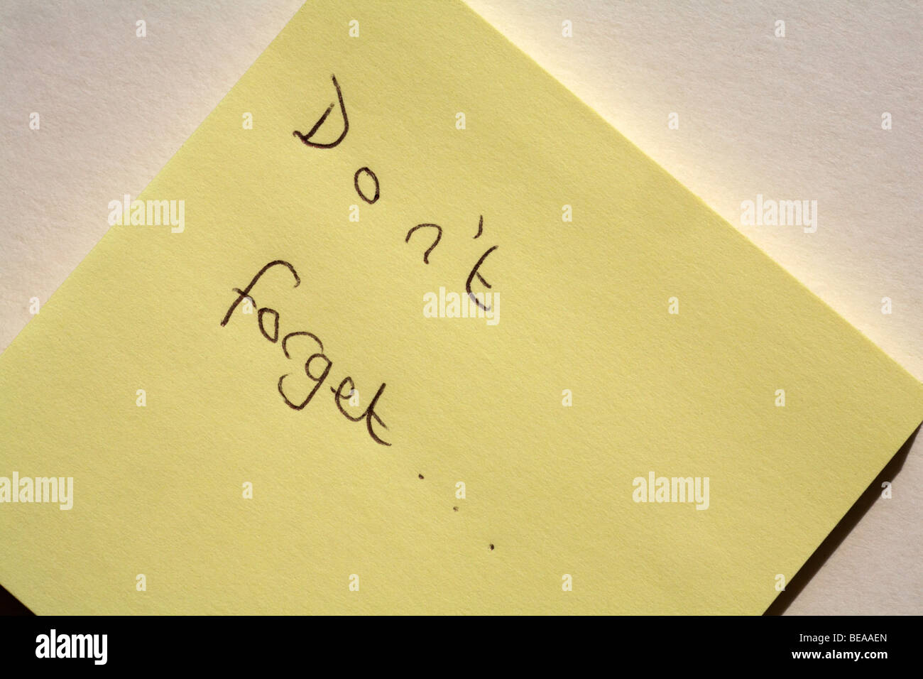 Don't forget reminder message written on yellow post-it note close up ...