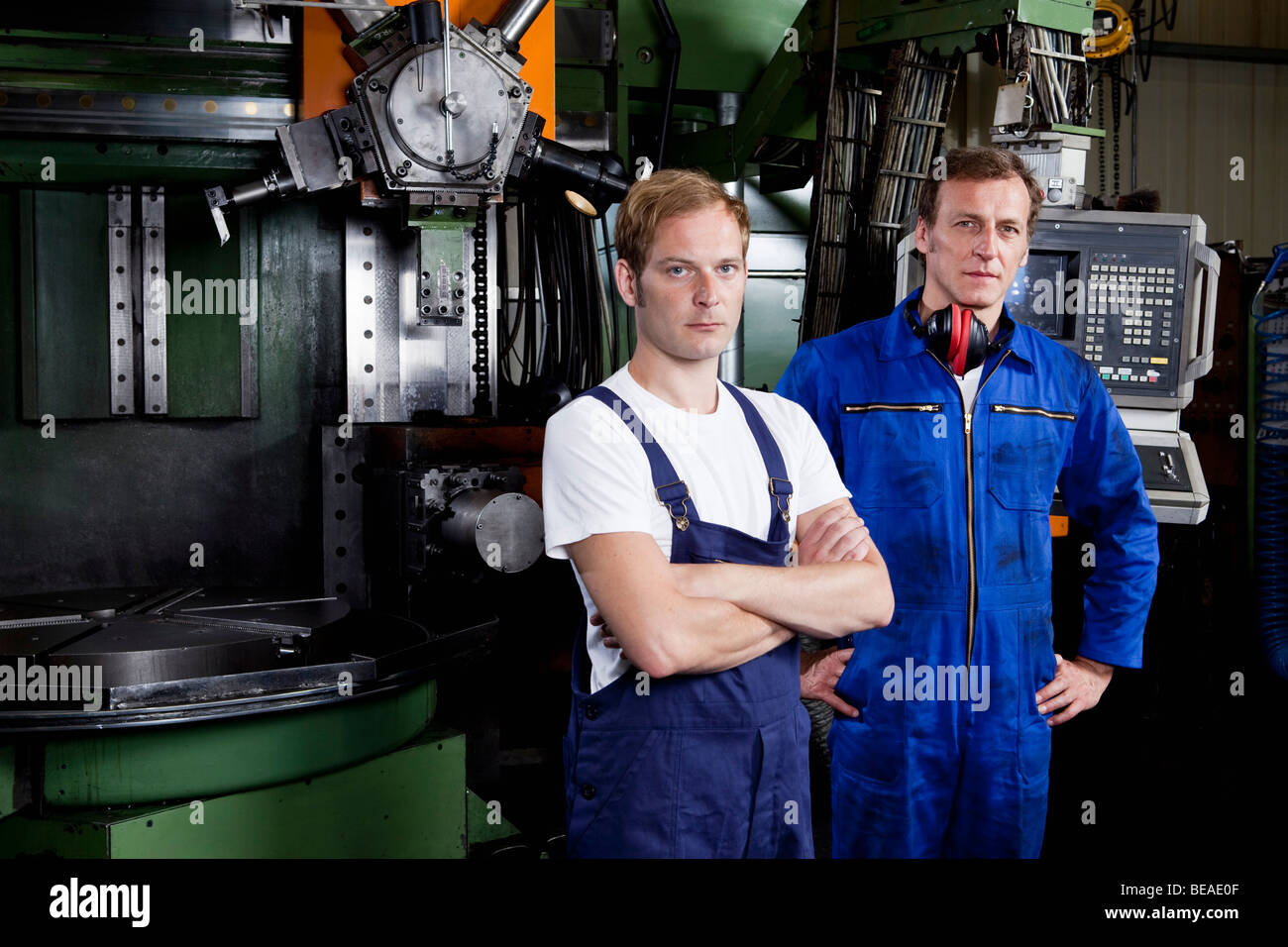 Portrait of two manual workers in a metal parts factory Stock Photo - Alamy