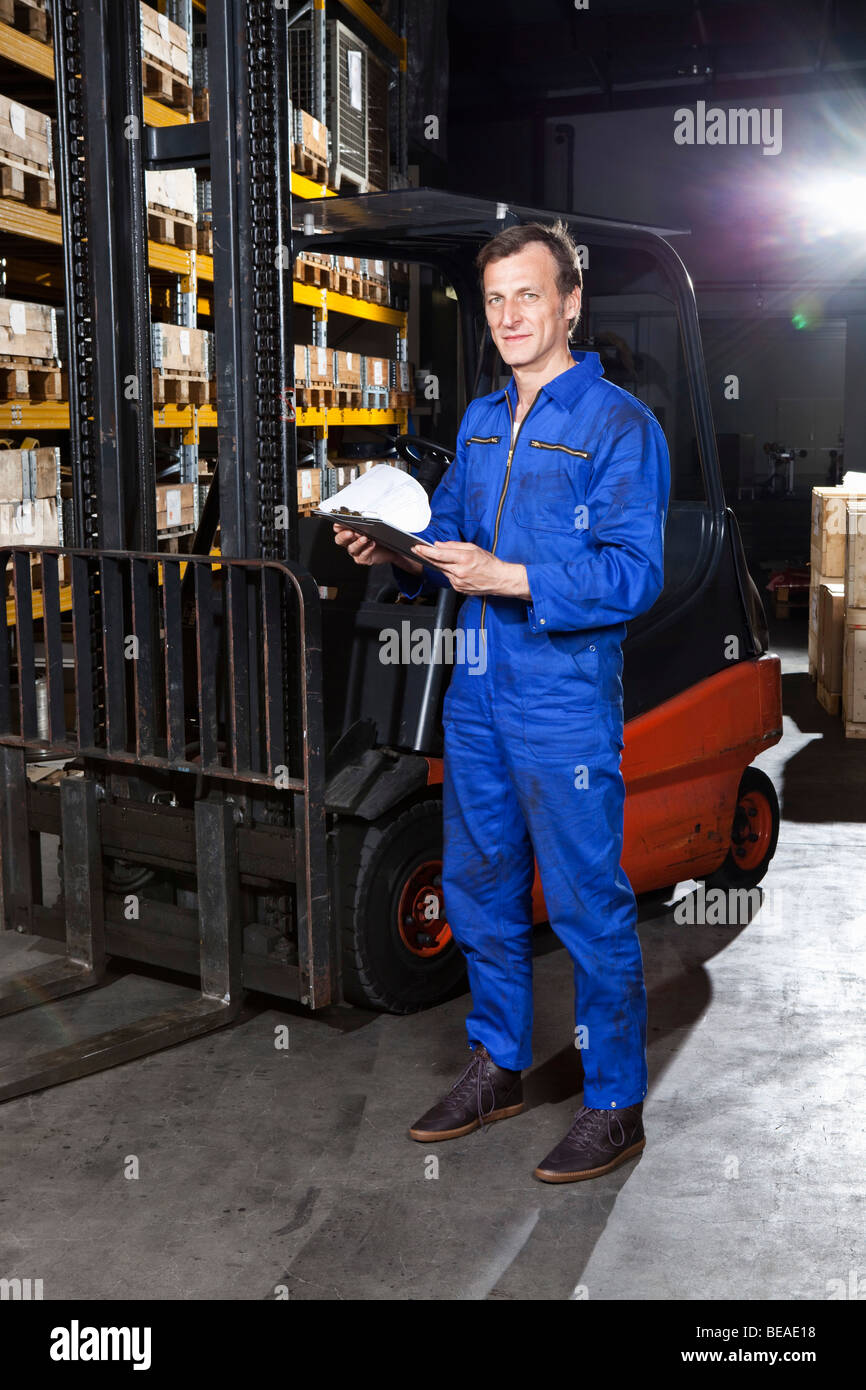 A manual worker holding a checklist in a metal parts warehouse Stock ...