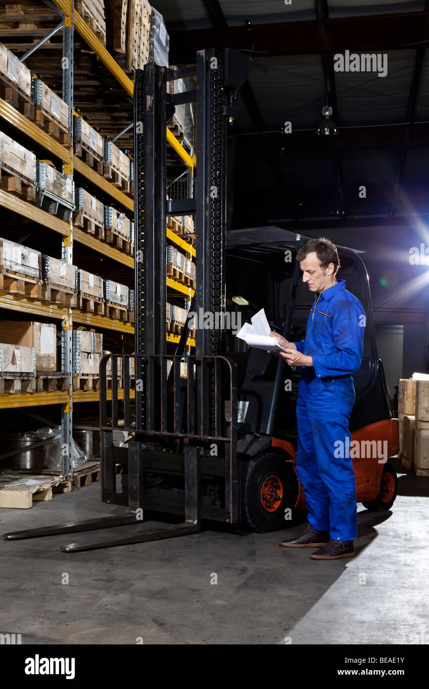 A manual worker looking at a checklist in a metal parts warehouse Stock ...