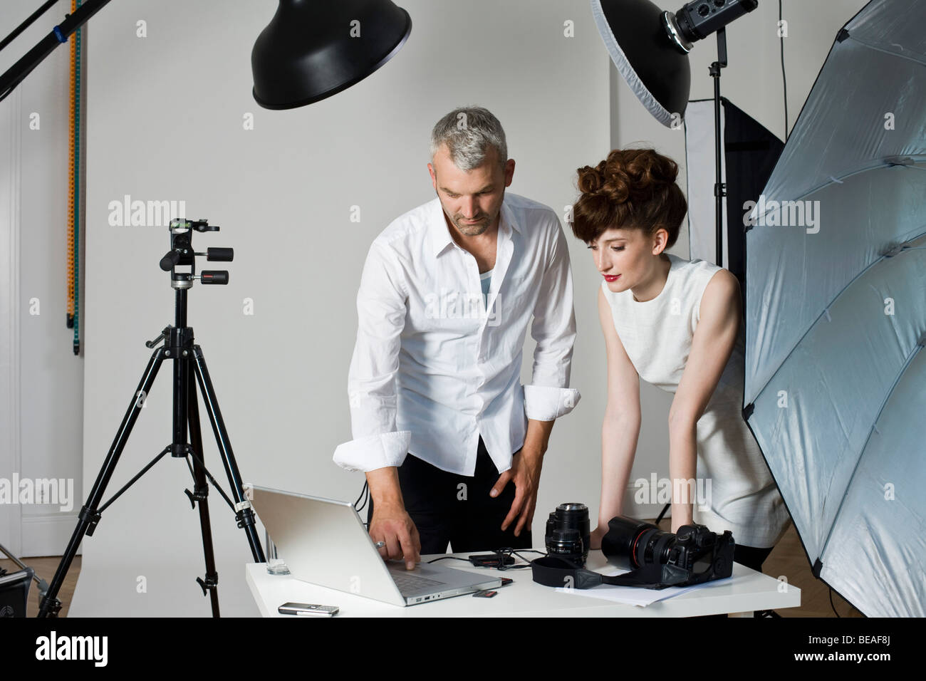 A model and a photographer looking at a laptop computer on the set of a ...