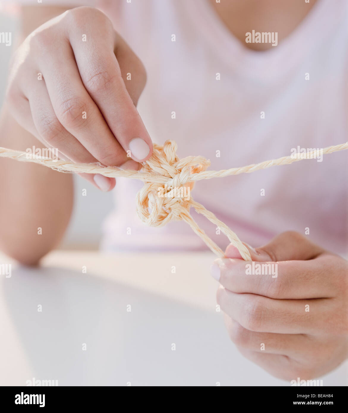 Woman tying knot in rope Stock Photo - Alamy