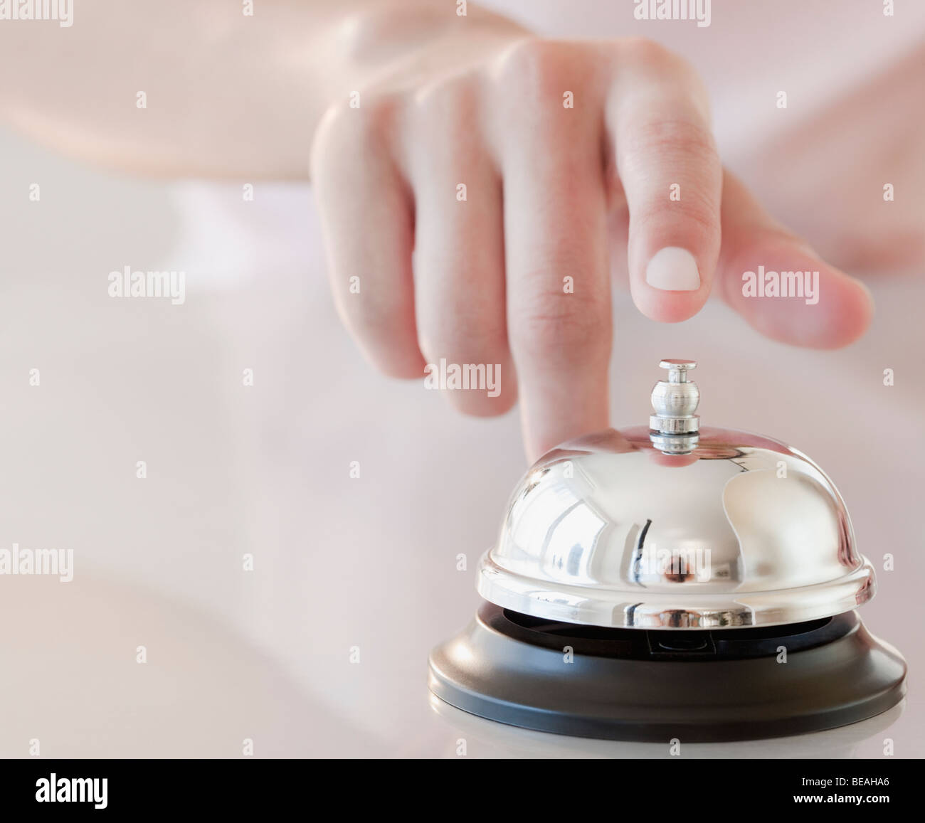 Woman tapping hotel service bell Stock Photo - Alamy